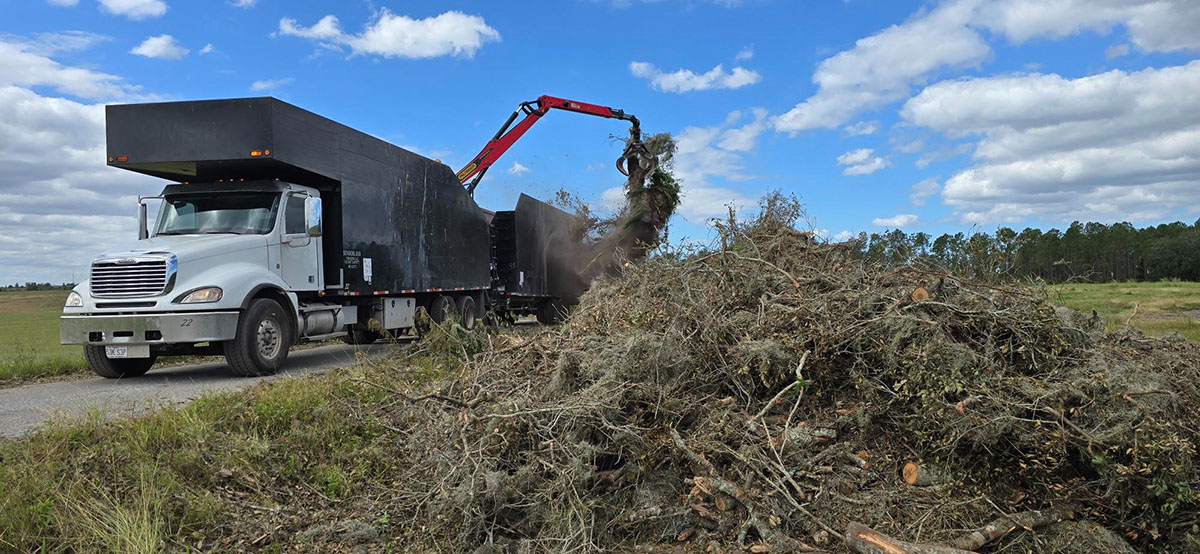 Debris truck with outstretched arm, collecting debris.